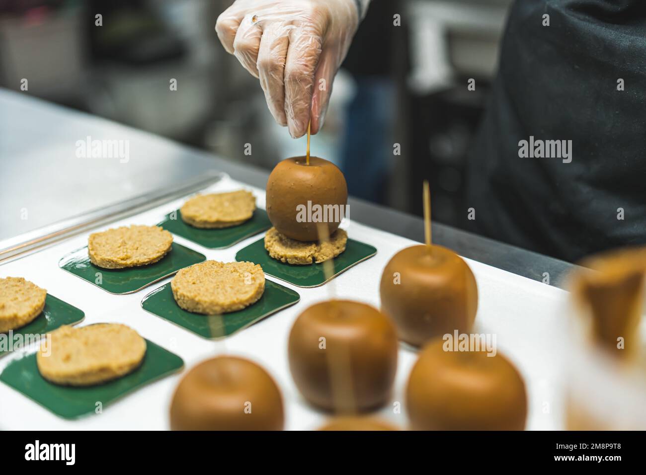 Unrecognisable professional baker assembling caramel apple dessert ...
