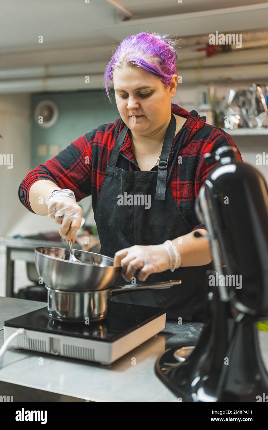 Professional female baker with purple dyed hair wearing black apron ...
