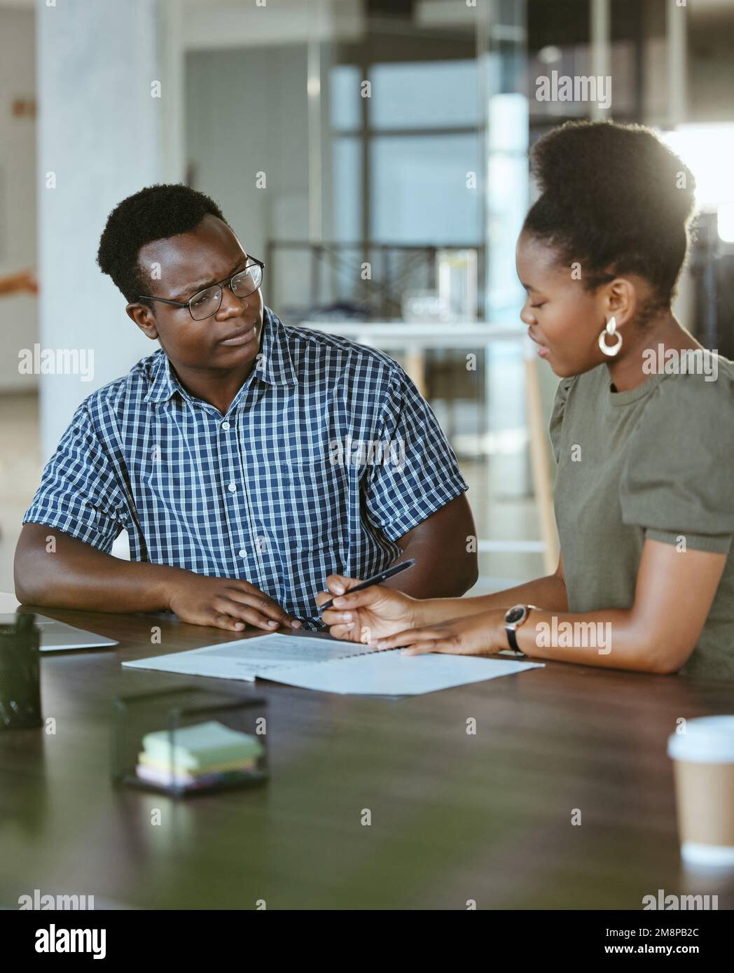 Two african american businesspeople having a meeting and looking at a ...