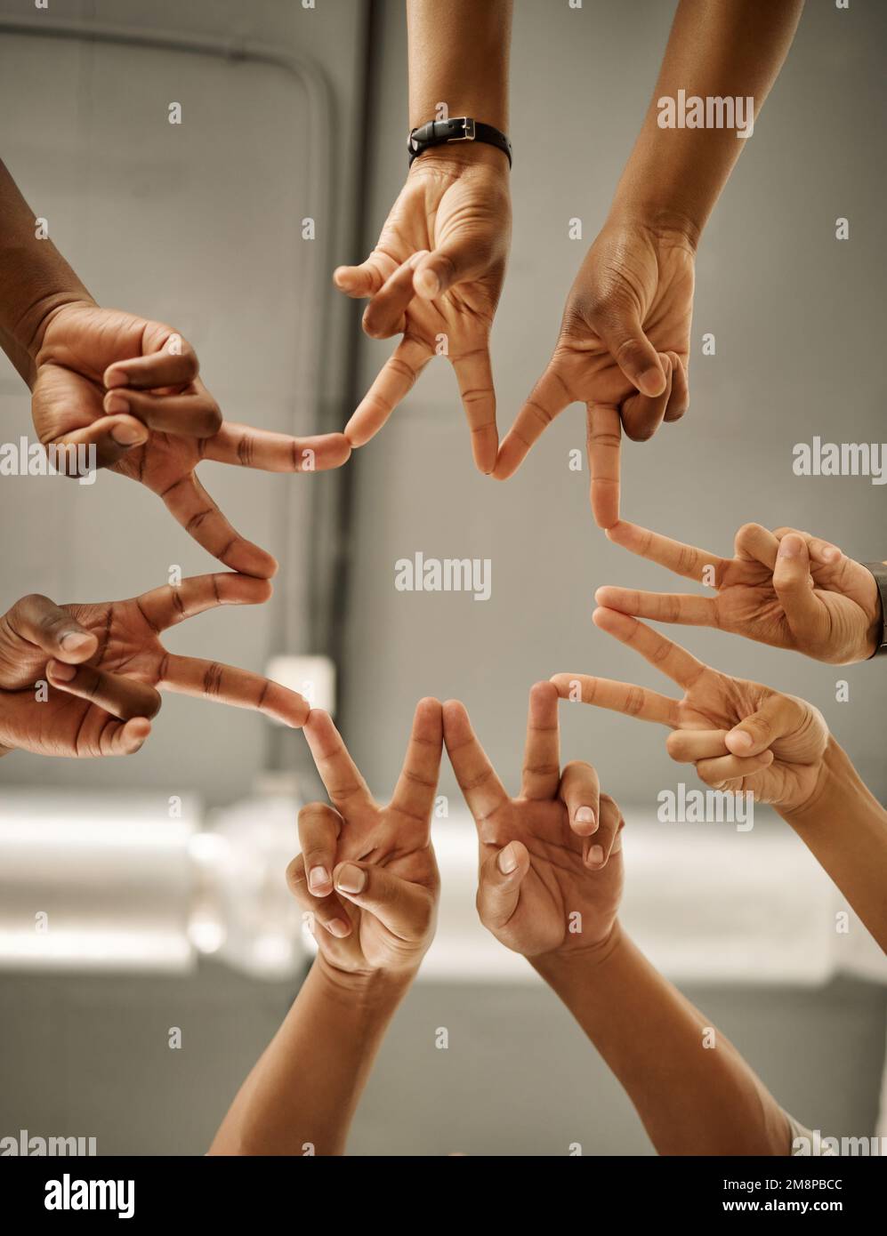 Closeup of hands of coworkers making peace signs in a star shape ...