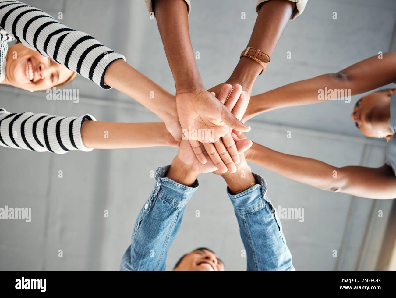 Group of businesspeople piling their hands together in an office at ...