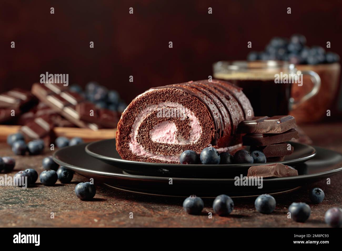 Chocolate roll cake with blueberries and a broken black chocolate bar ...