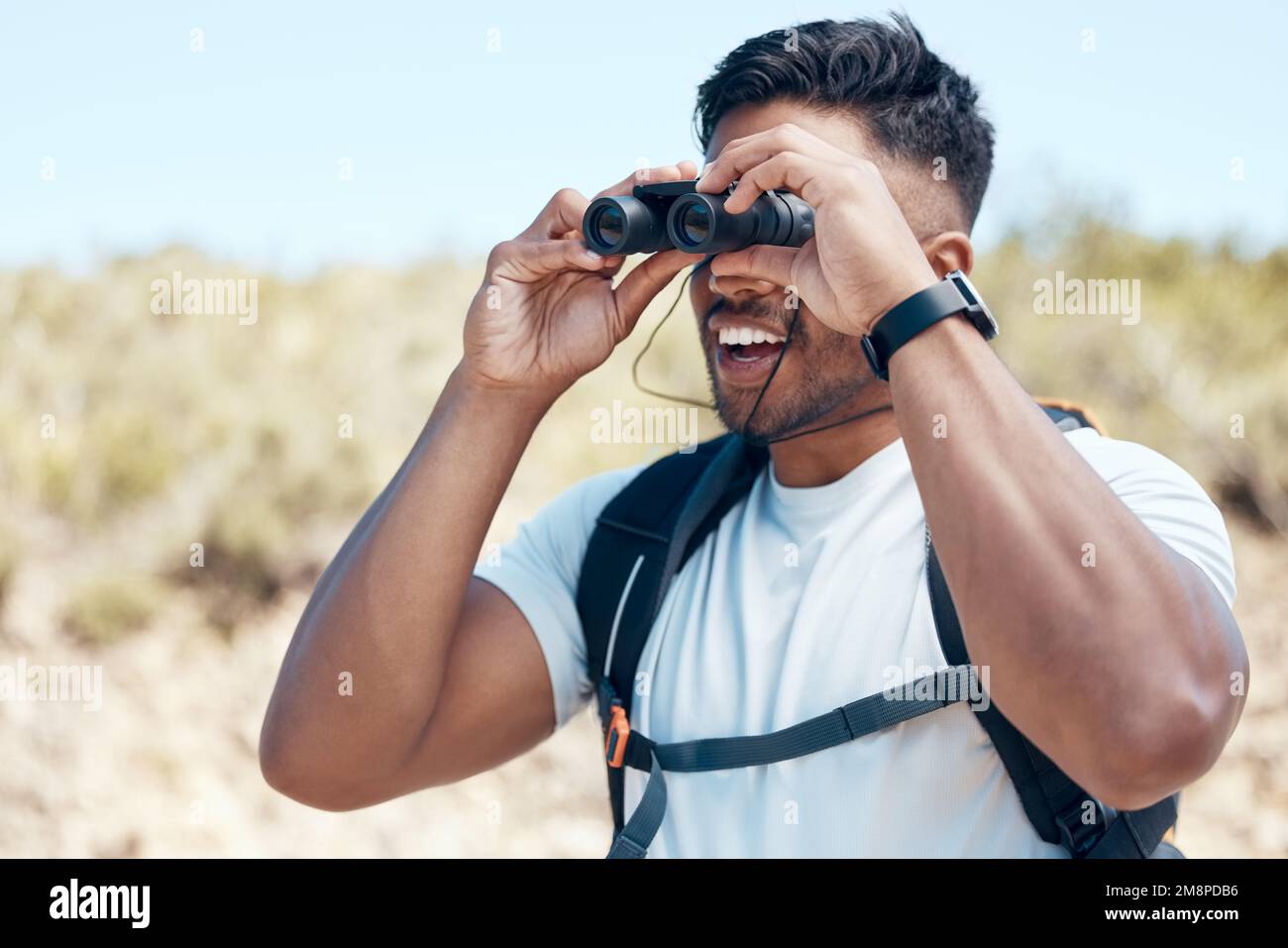 Closeup of a mixed race male using a binocular during a hike outside ...
