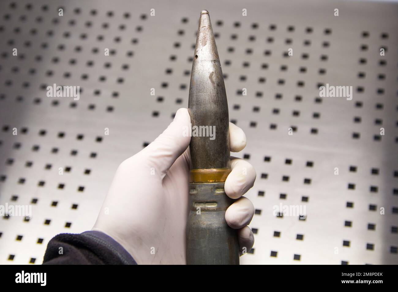 Projectile, cartridge, cartridge case in a man's hand in a rubber glove ...