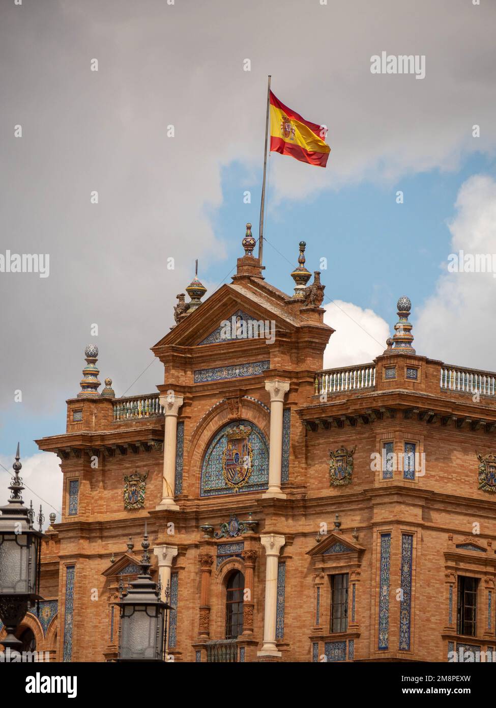 A vertical shot of a building with Spanish flag in the central square ...