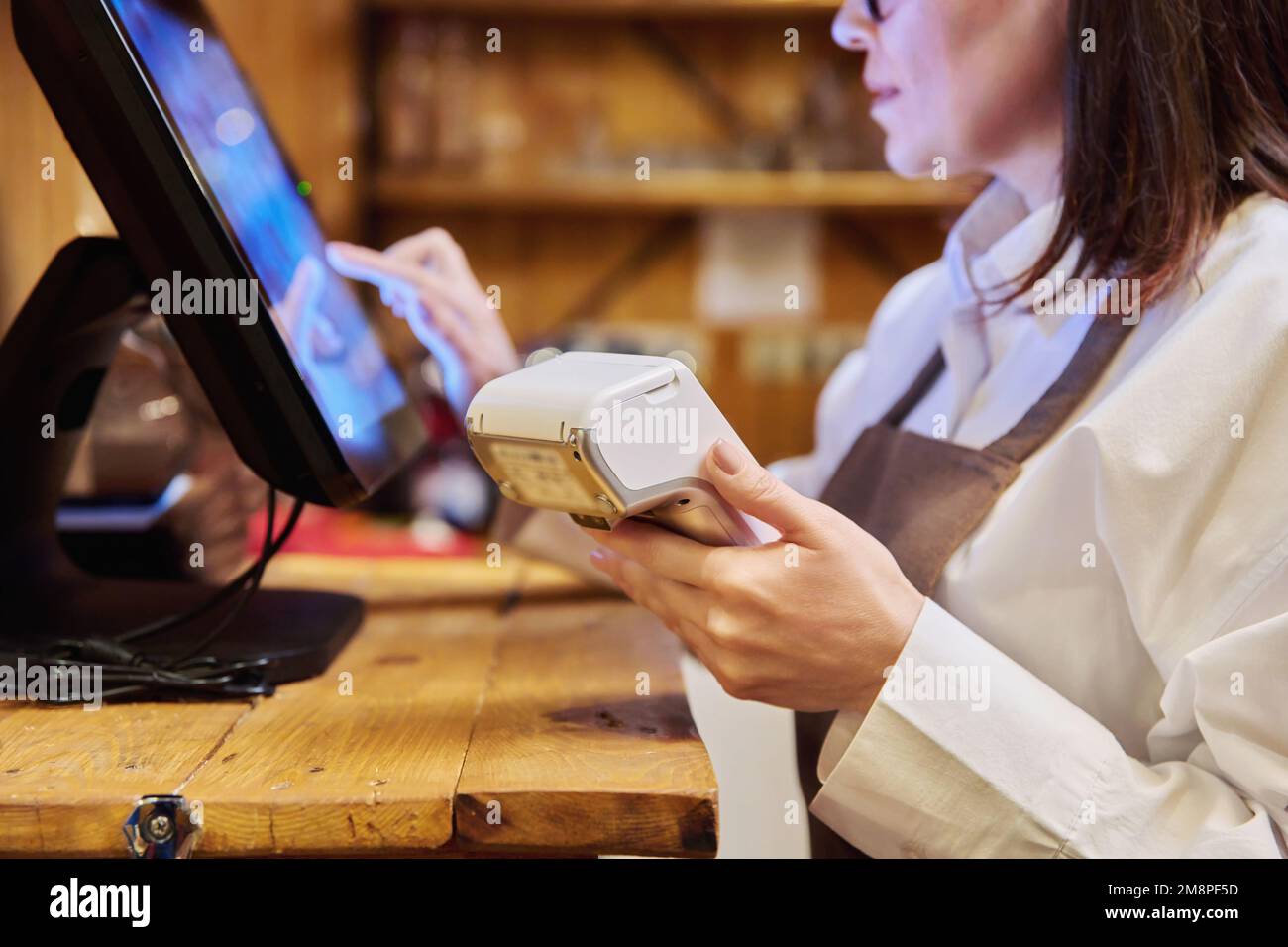 Female restaurant worker using computer terminal while serving ...