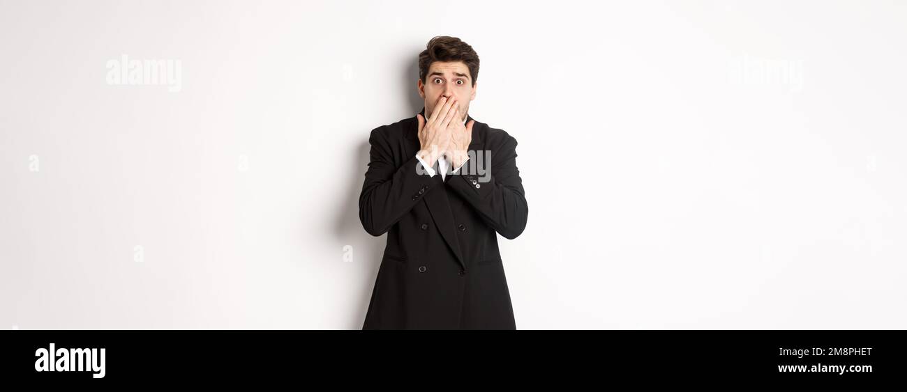 Scared man in formal suit, gasping and looking frightened at camera ...