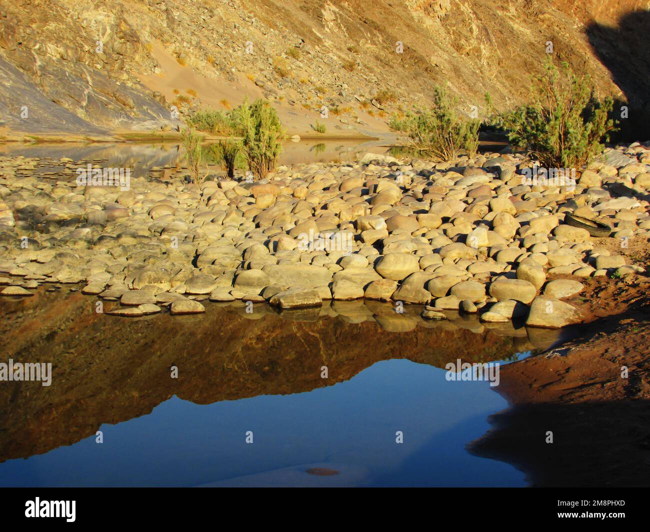 Cliffs of the rim of the Fish River Canyon reflecting into a calm ...