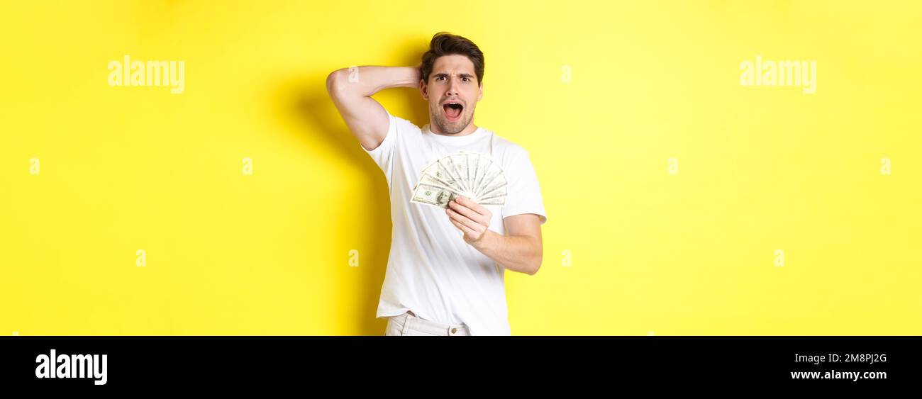 Frustrated man holding money, shouting and panicking, standing over ...