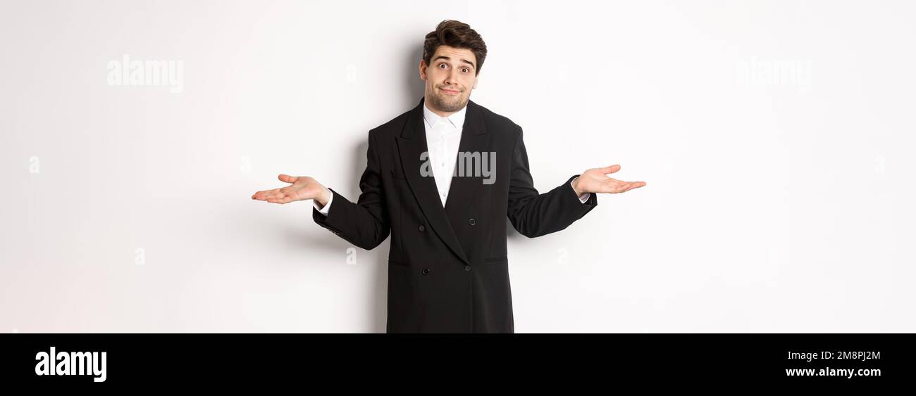 Image of handsome confused man in black suit, shrugging and looking ...