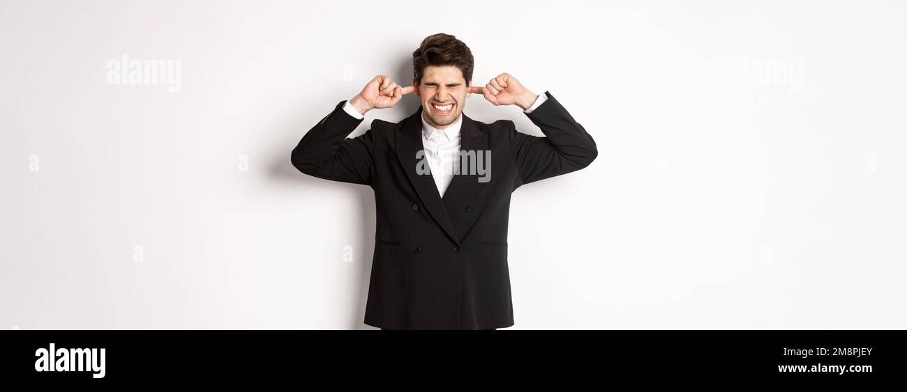 Portrait of annoyed and bothered businessman in black suit, shut ears ...