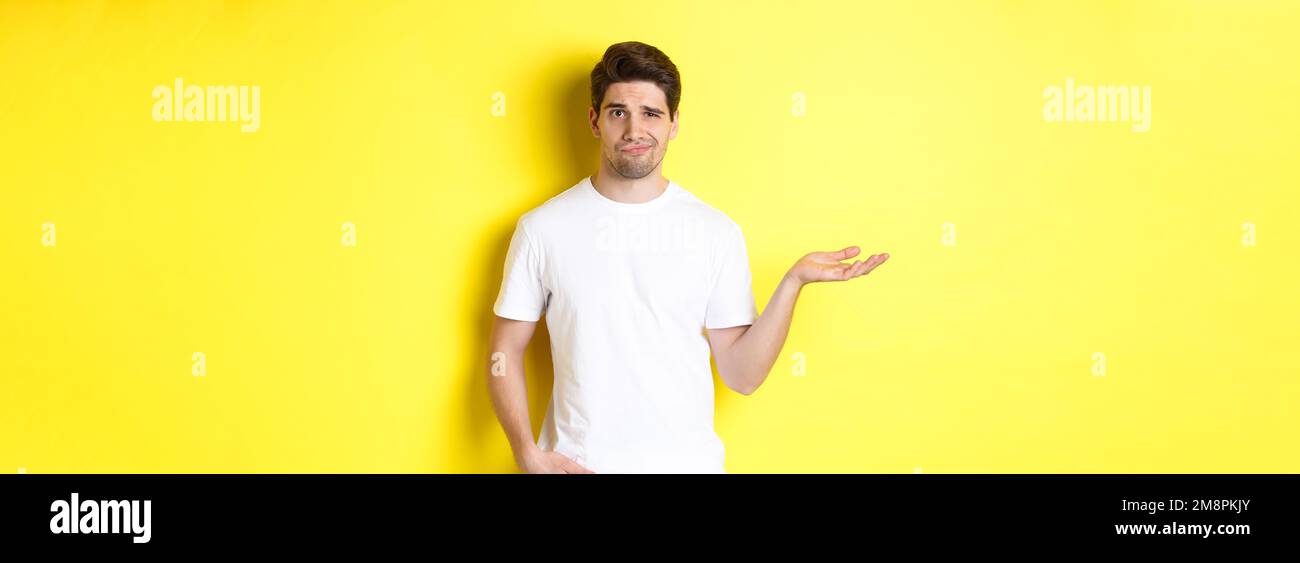 Confused and displeased guy raise hand, grimacing puzzled, standing ...