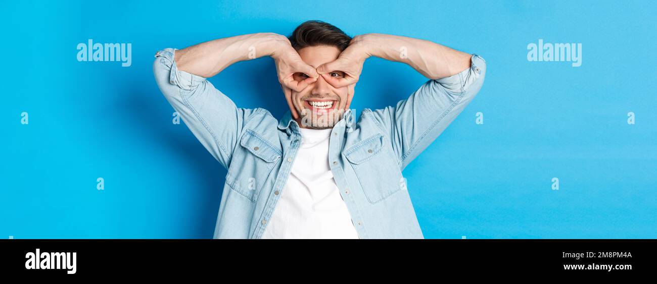 Young caucasian guy showing funny expression, making superhero mask ...