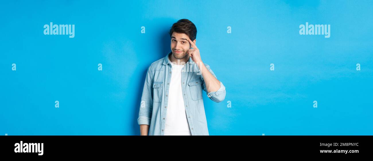 Young thoughtful man pointing at head, asking to think about it, giving ...