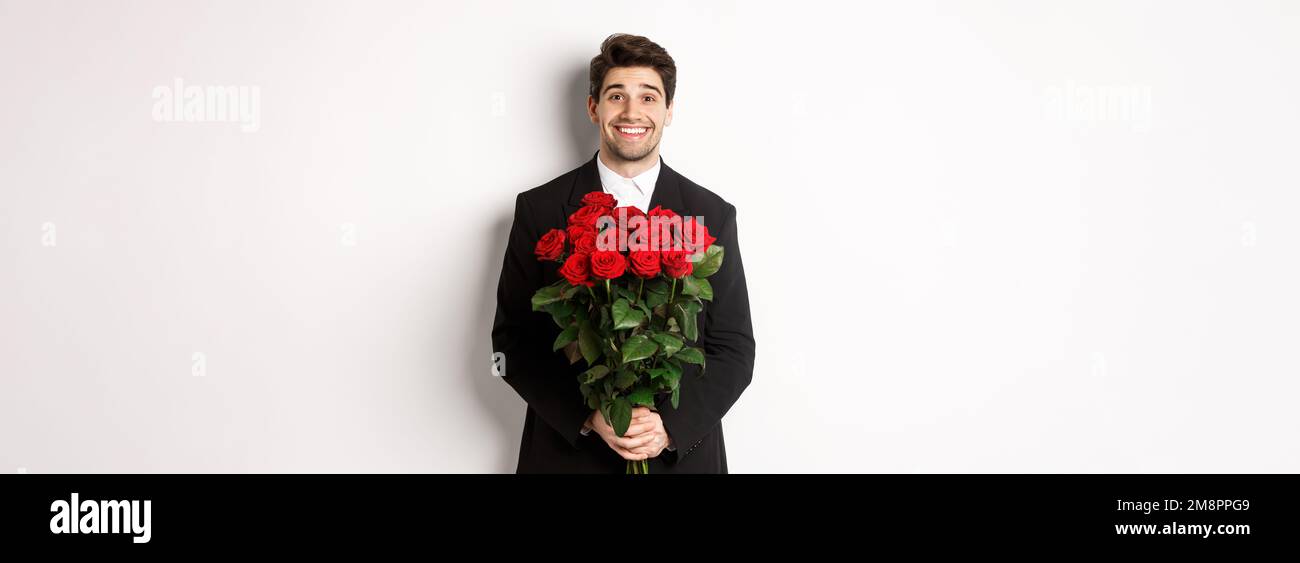 Image of handsome man in black suit, holding bouquet of roses and ...