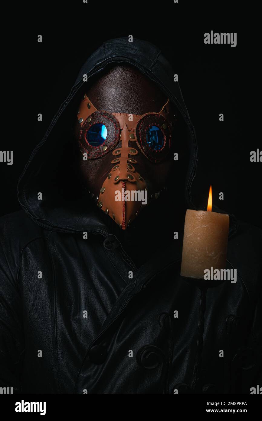 Plague doctor with crow-like mask and candle isolated on black ...