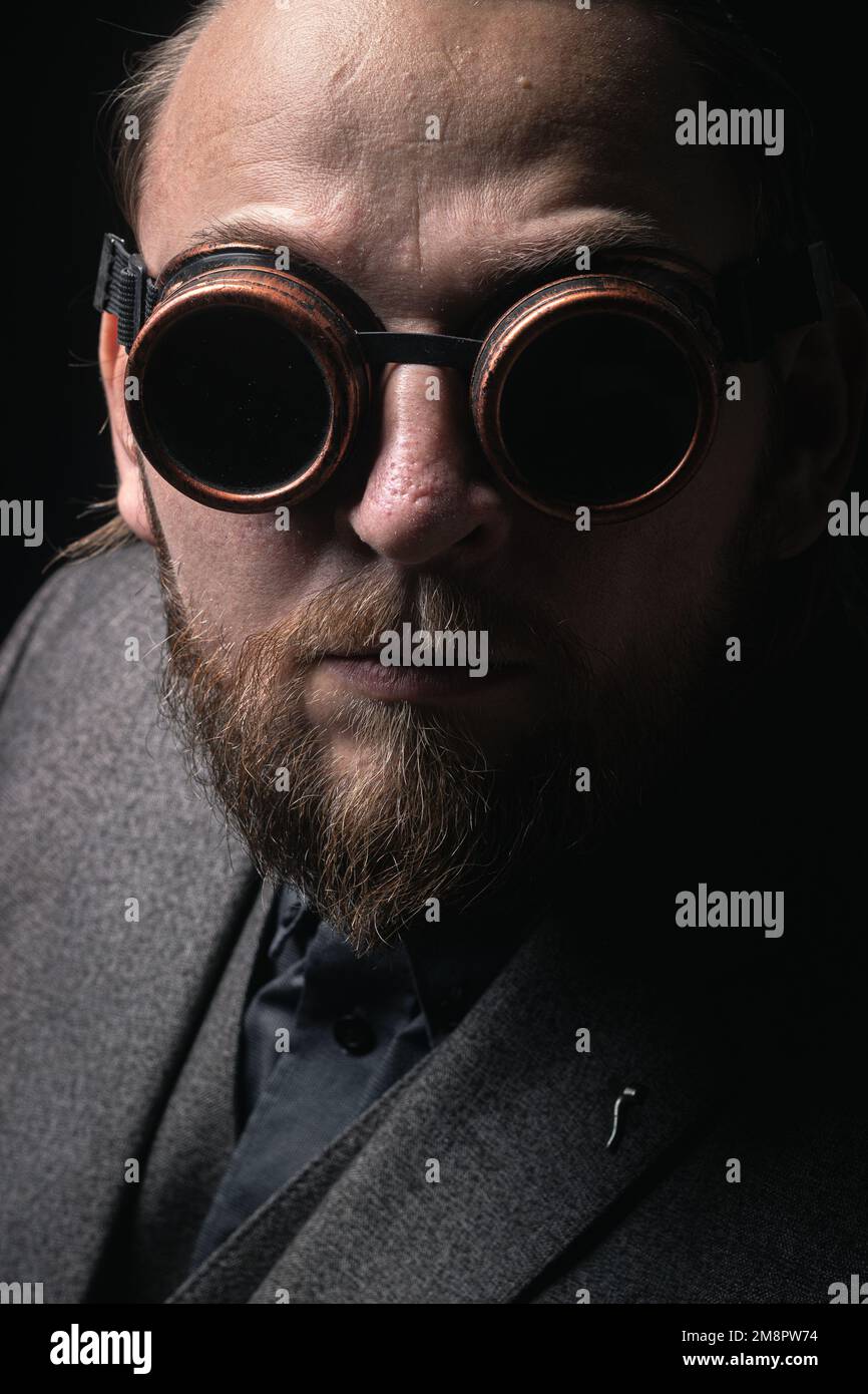 charismatic man in a classic suit and steampunk goggles on a black ...