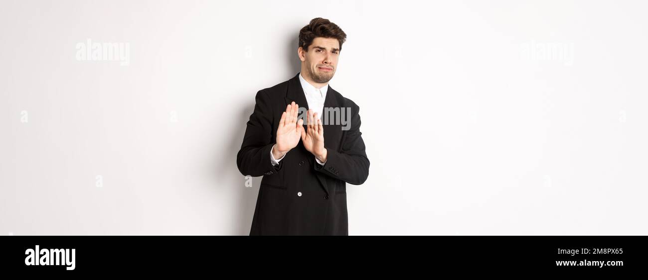 Image of stylish handsome man in black suit, cringe from something ...