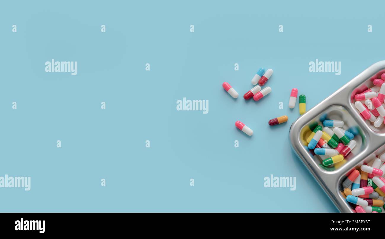 Above view of Colorful antibiotic capsule pills on a tray and blue ...