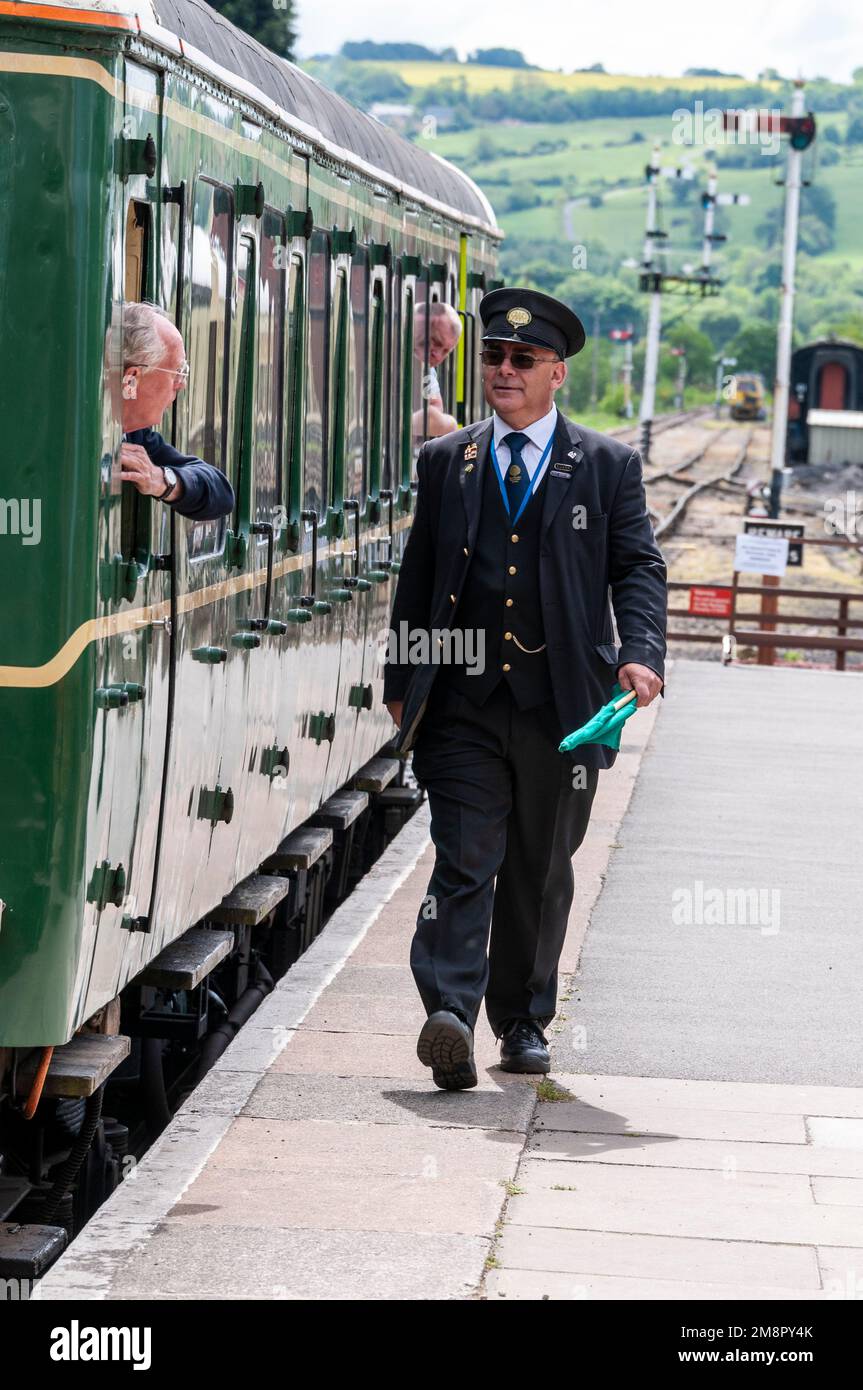 A train guard walks along the platform beside a BR Class 122 DMU ...