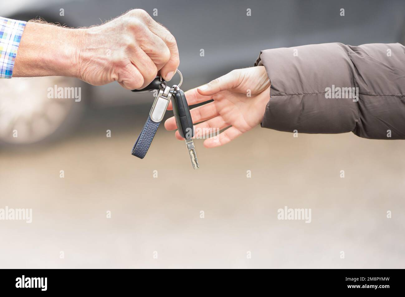 car key hands over Businessman a young woman in front of blurred car ...