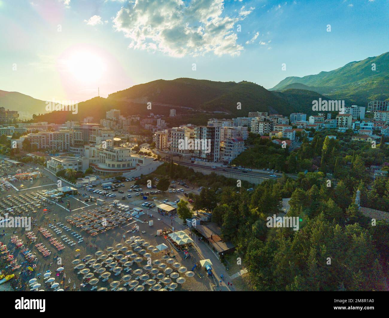 Wide sandy beach with sun umbrellas, plastic white sunbeds and people ...