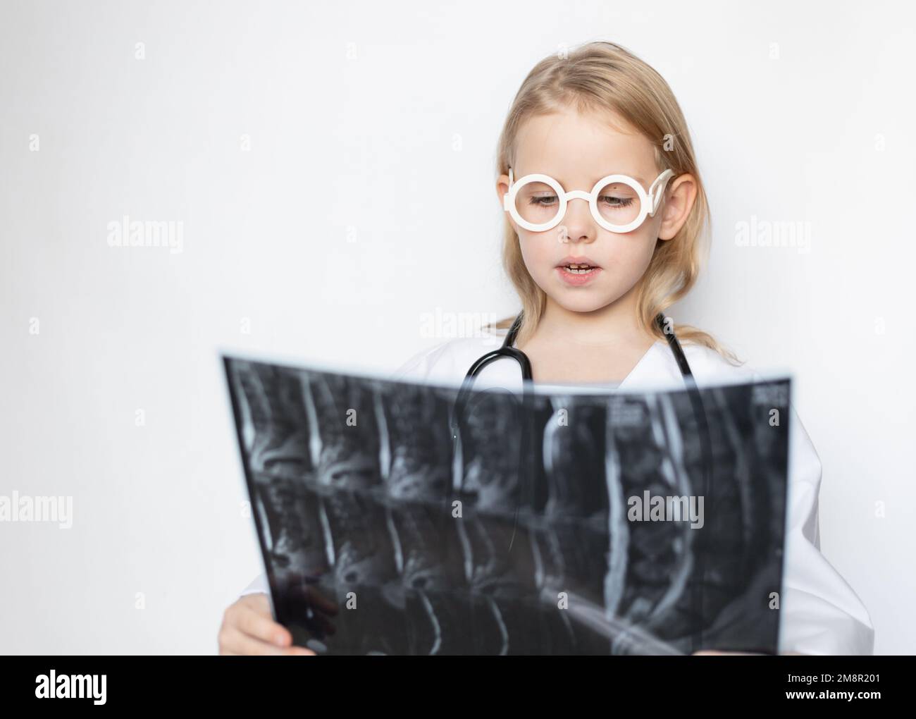 Caucasian child dressed up in doctor uniform with eyeglasses and ...