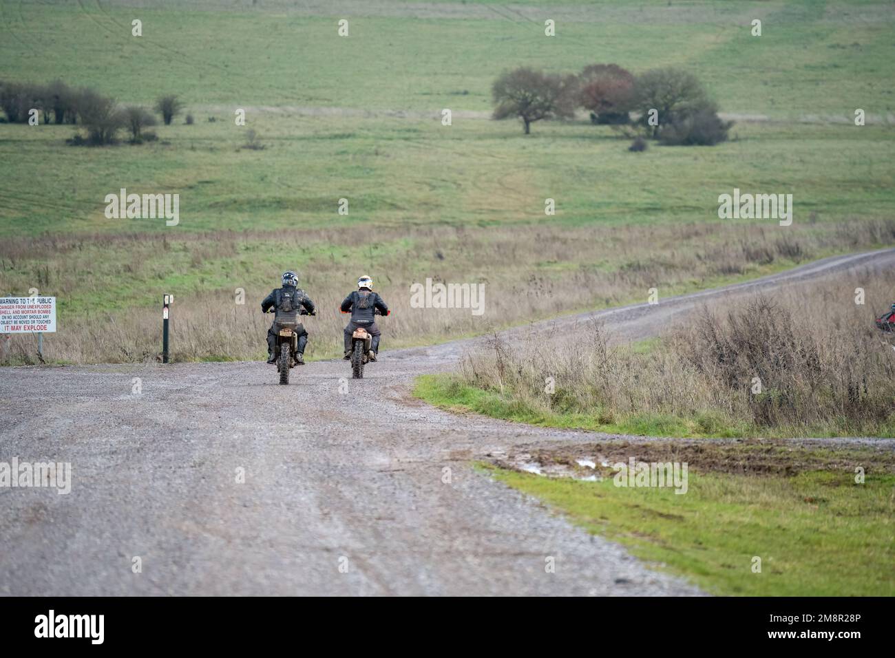 motor cyclists (bikers) riding off-road motorbikes along a stone track ...