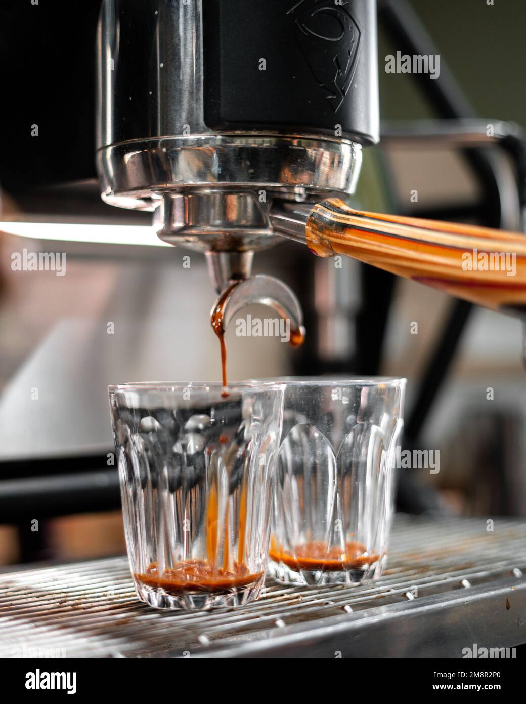 A vertical shot of coffee dripping from the machine into glass cups ...