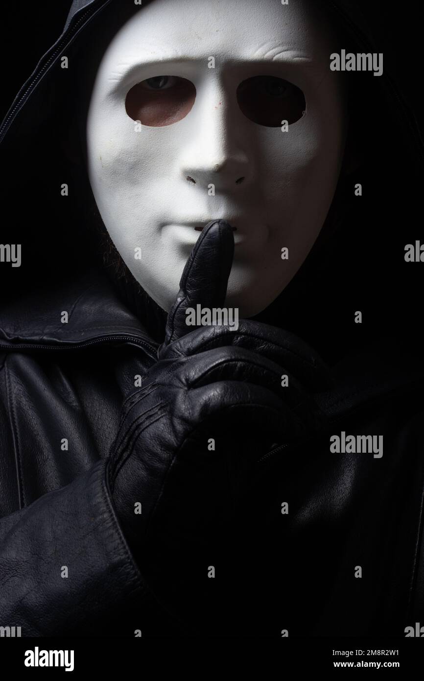 Man in terrible face mask staring at camera against dark background ...