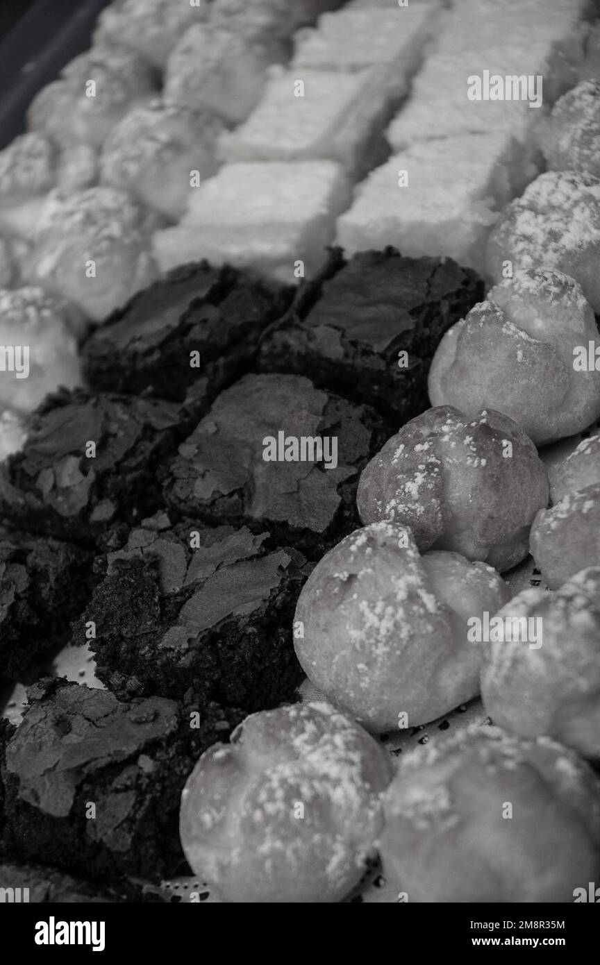 A vertical shot of chocolate cakes in grayscale served on a large ...