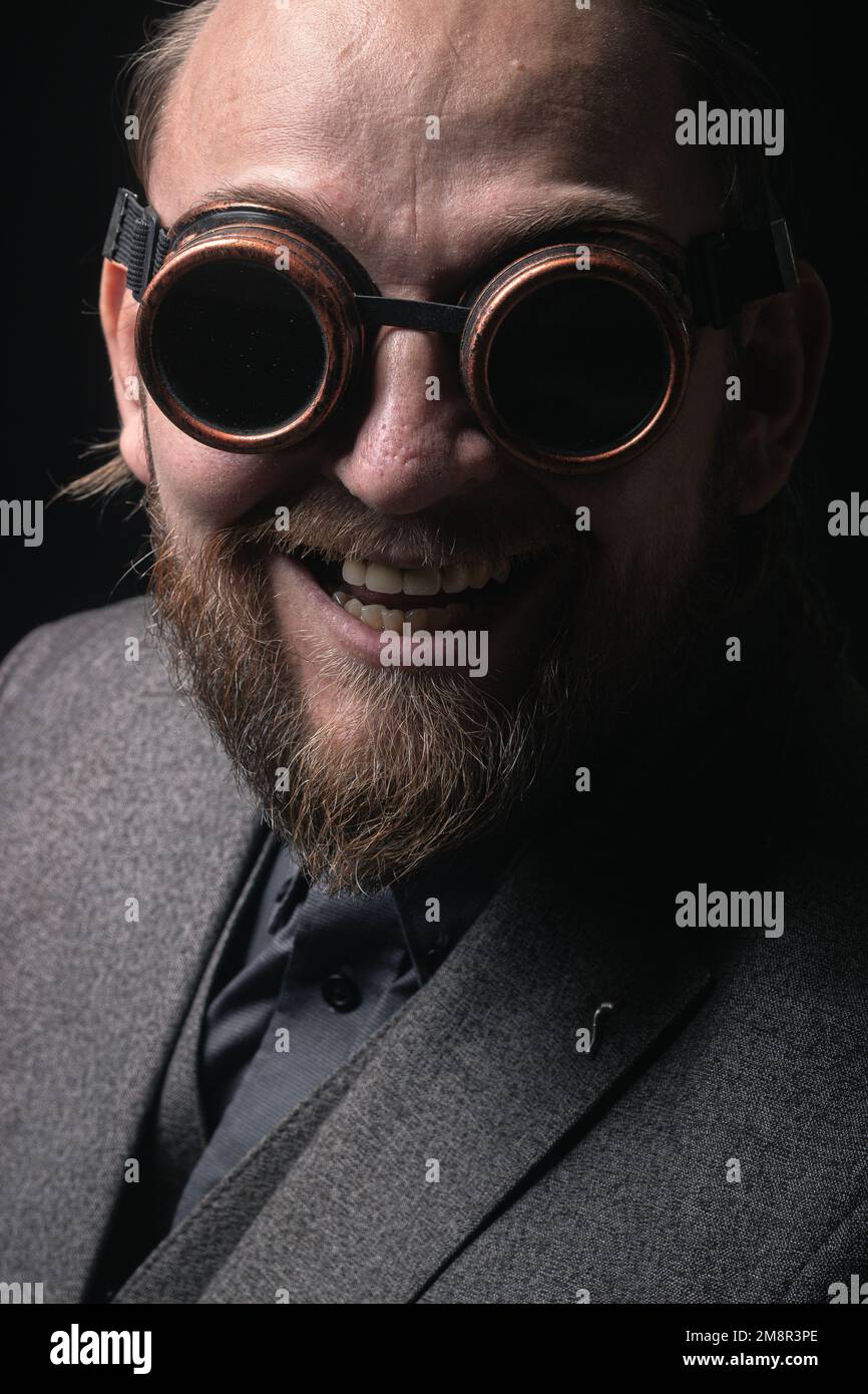 charismatic man in a classic suit and steampunk goggles on a black ...