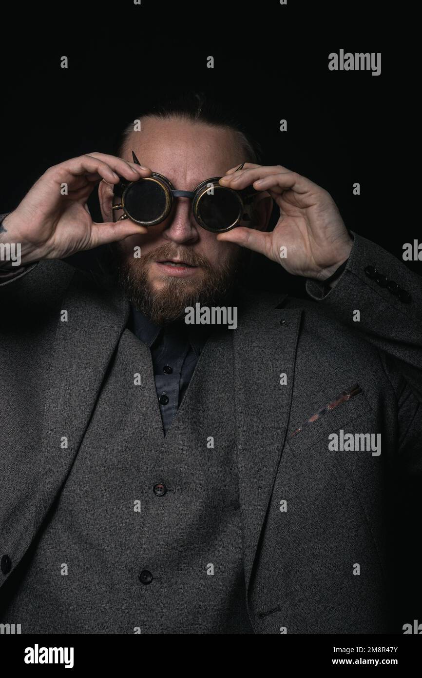 charismatic man in a classic suit and steampunk goggles on a black ...