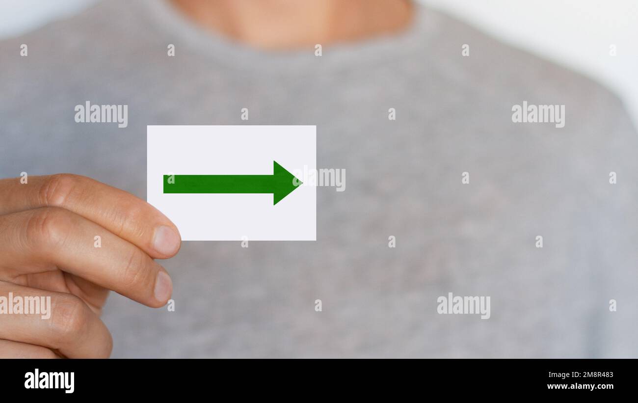 Man holding a right arrow sign. Green arrow pointing to the right. The ...