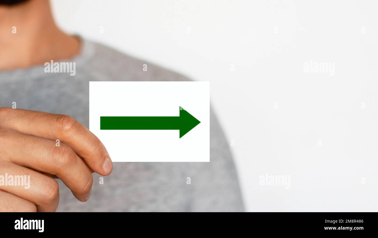 Man holding a right arrow sign. Green arrow pointing to the right. The ...