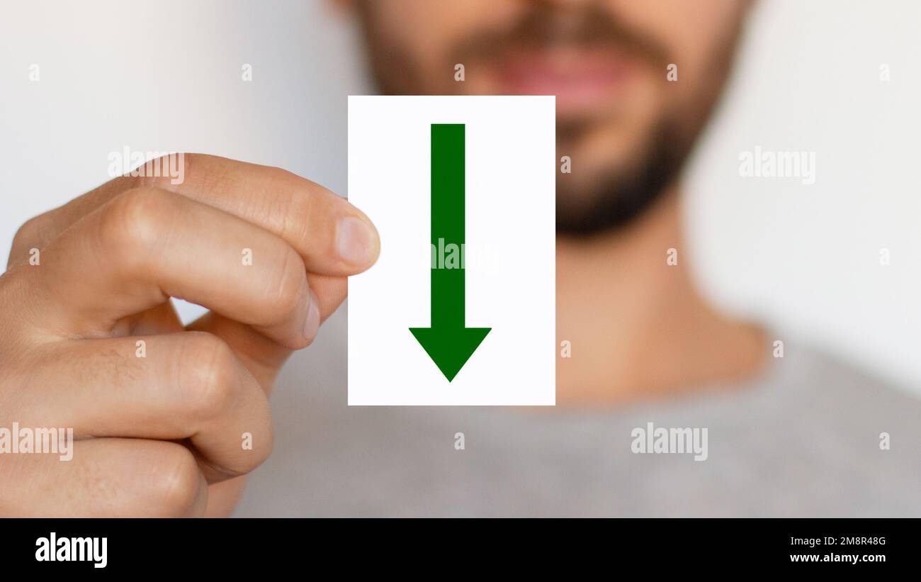 Man holding down arrow sign. Green arrow pointing down. The male ...