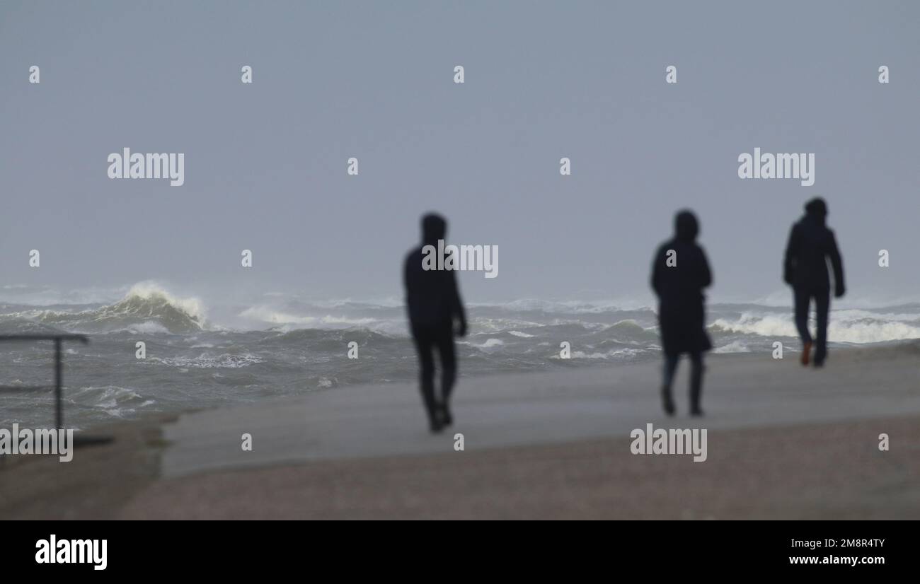 Norderney, Germany. 15th Jan, 2023. Strollers walk along the whipped up ...