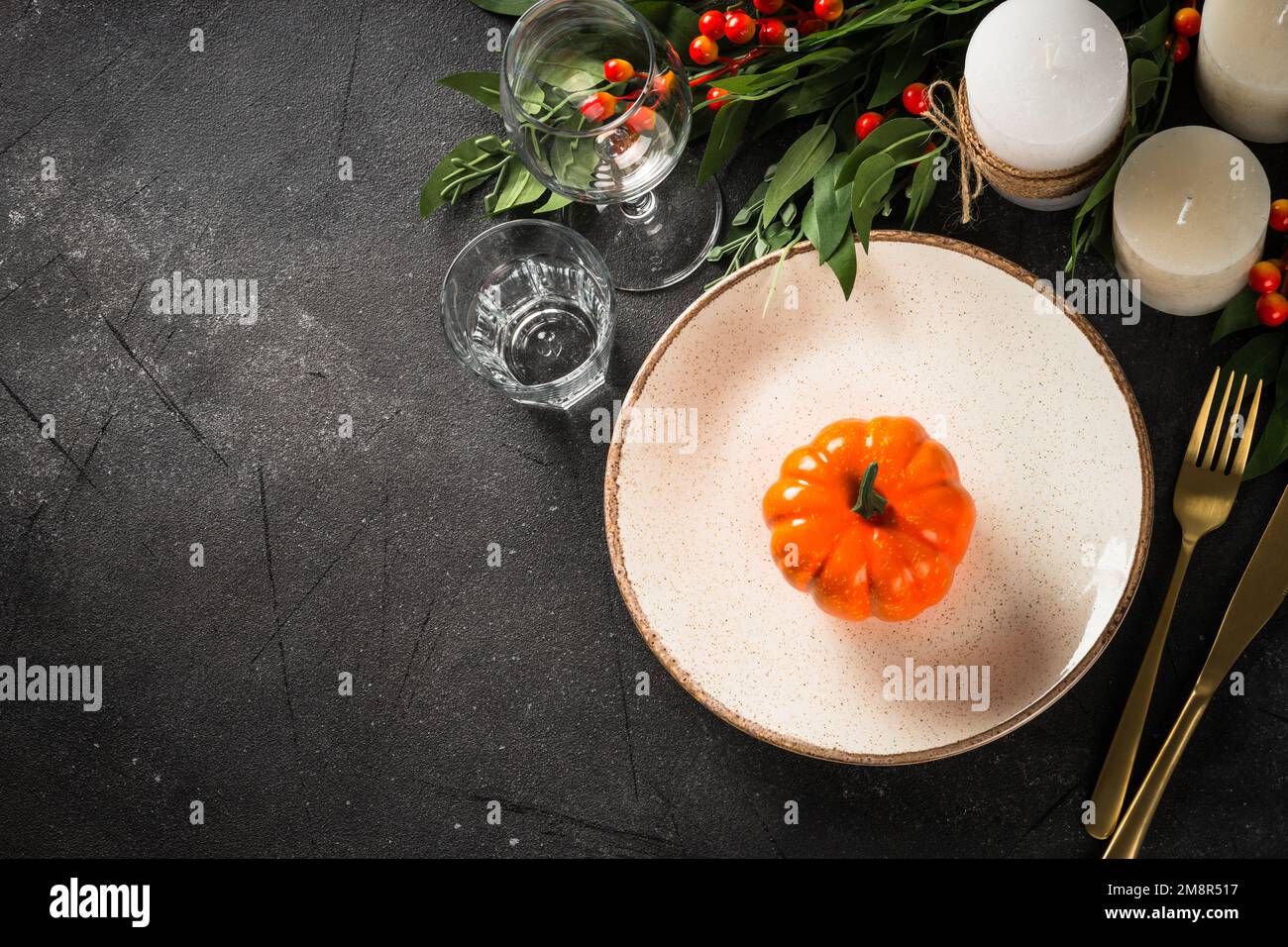 Autumn table setting with plate, cutlery, pumpkin and candles ...