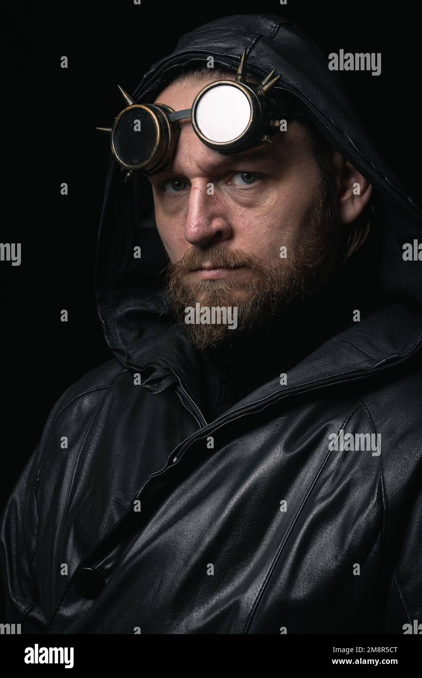 A man in a hood, wearing vintage steampunk goggles looking at the ...