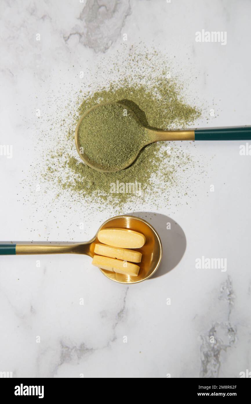Green powder and pills in spoons. Concept of nutritional supplement ...