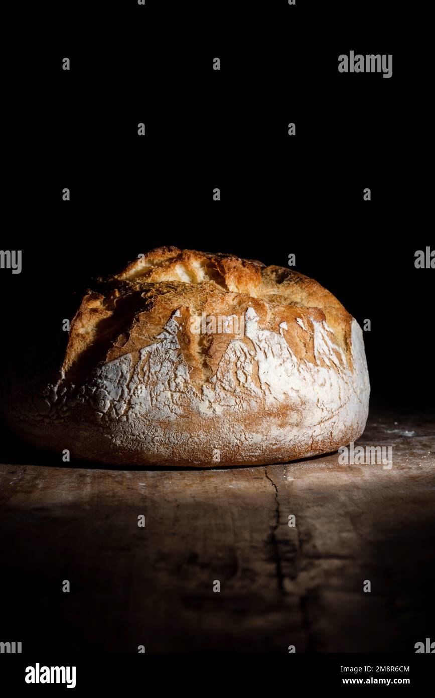Boule or rustic loaf of french bread on an old wooden table on a black ...