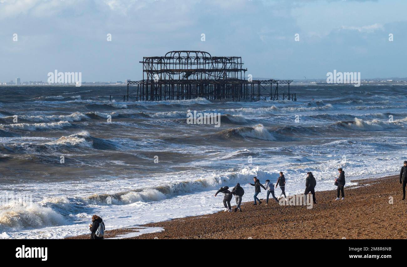 Brighton UK 15th January 2023 - Visitors enjoy dodging the waves on a ...