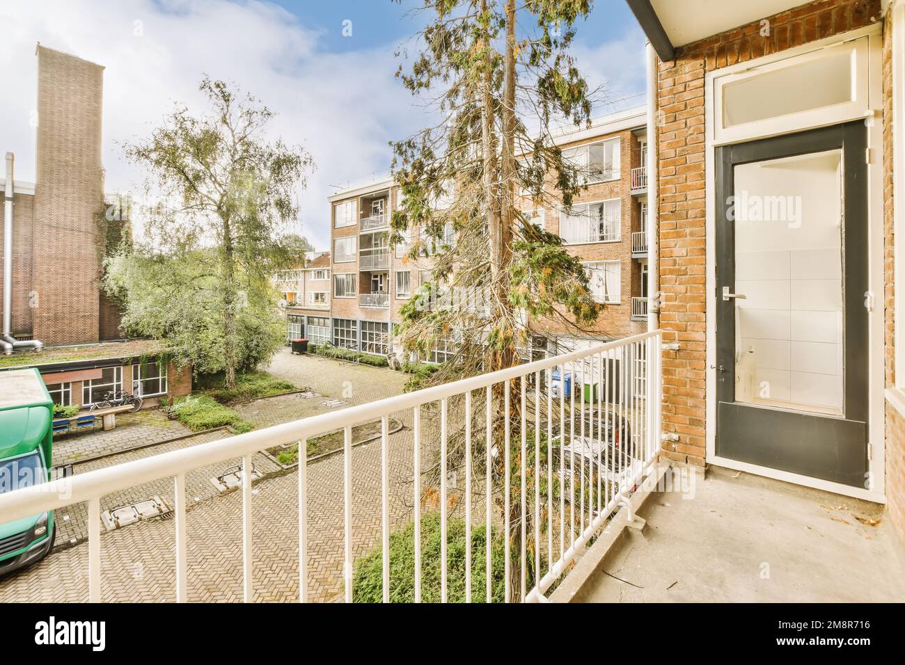 a balcony with trees and cars parked on the street in front of an ...
