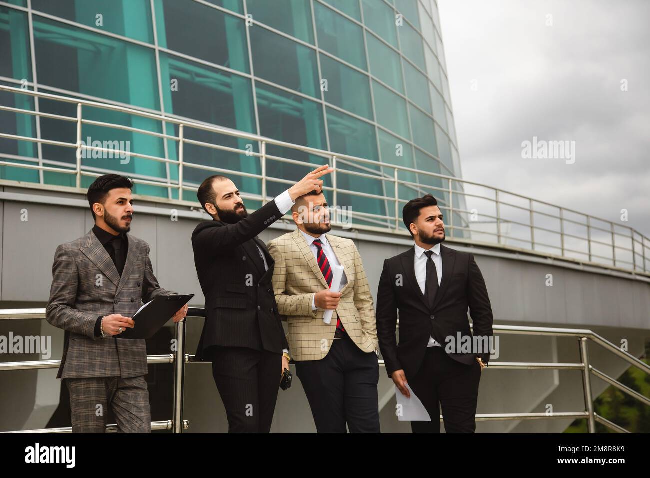 Business people outdoor meeting. Male employees in suits communicate ...