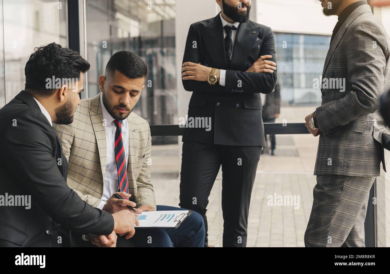 Business people outdoor meeting. Men in jackets discuss working moments ...