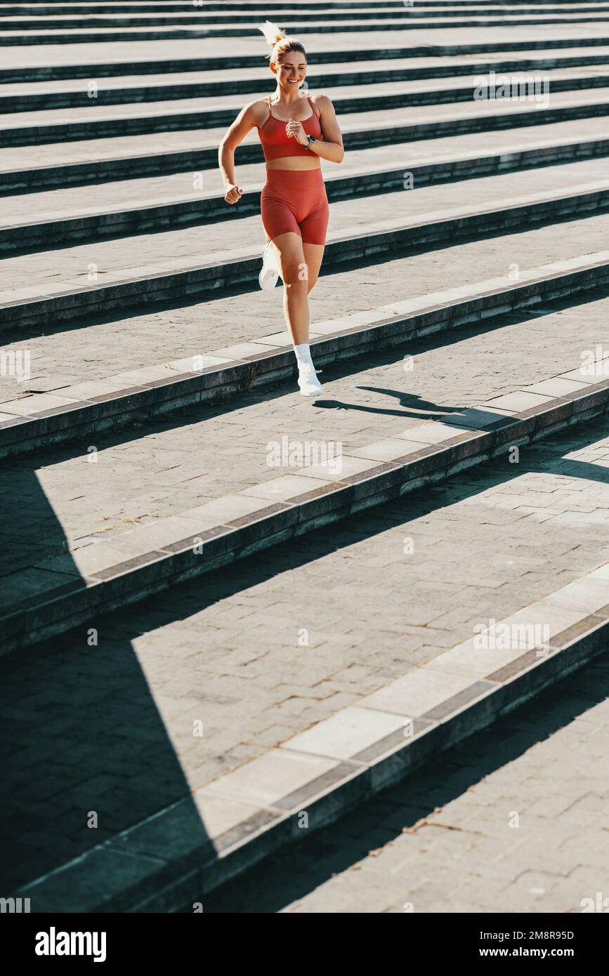 Female runner exercising down the stairs outdoors. Sporty woman doing a ...