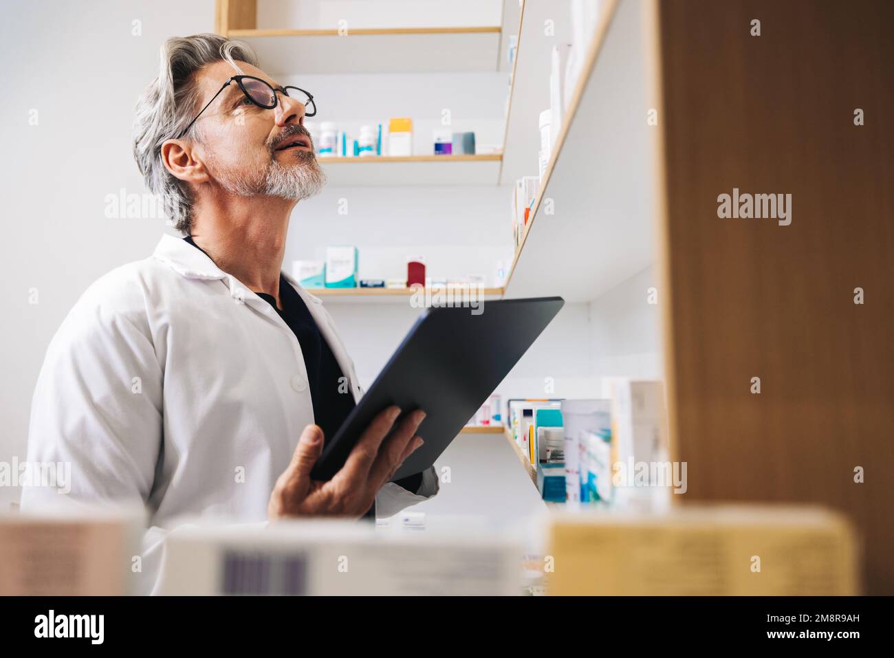 Pharmacist looking for prescription medication on a drug store shelf ...
