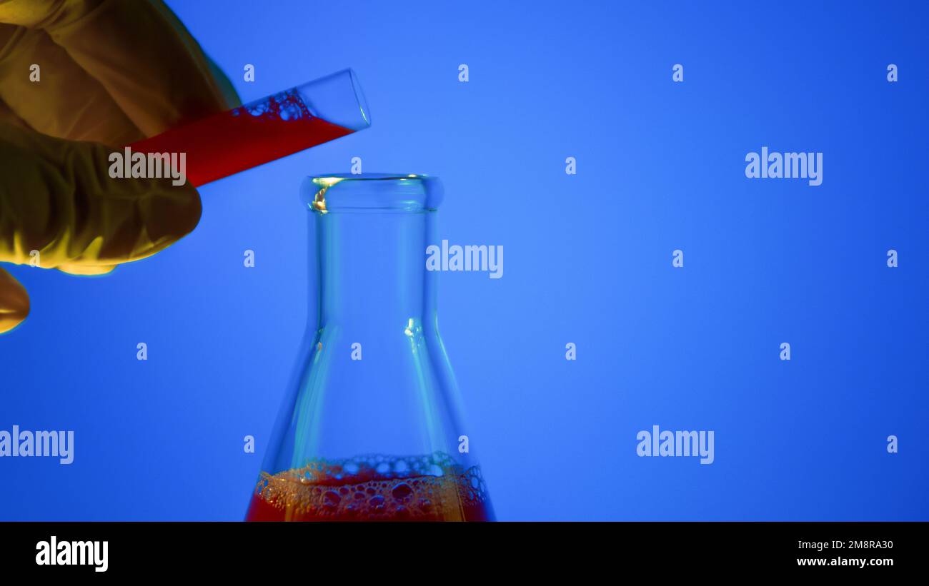 A hand in a medical glove is waiting for a test tube. On a blue ...