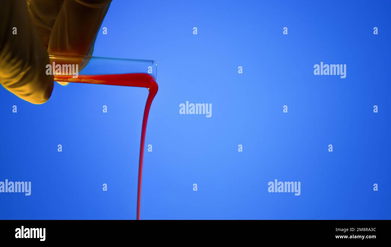 A hand in a medical glove is waiting for a test tube. Liquid is pouring ...