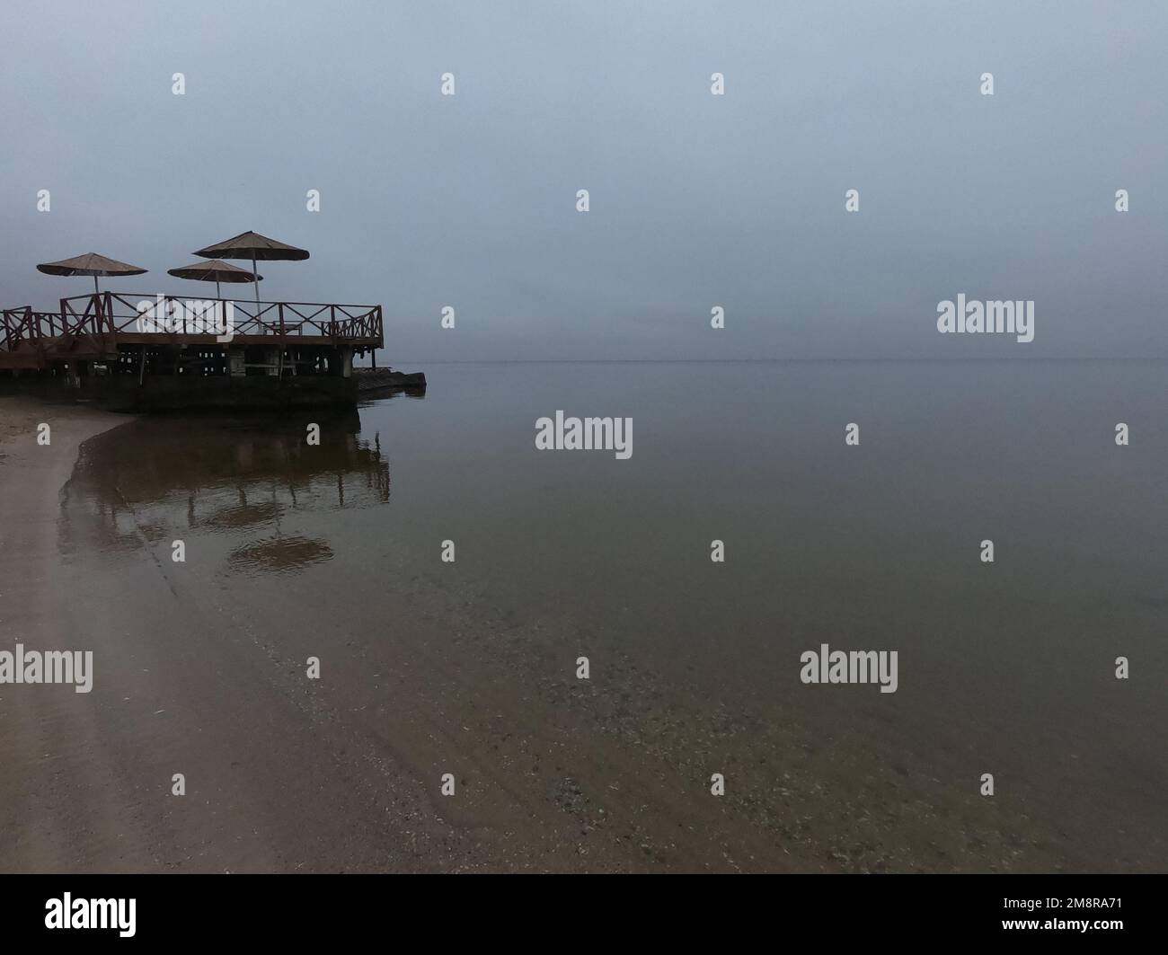 Sandy beach on calm sea. Calm sea cloudy weather. Smooth waveless sea ...